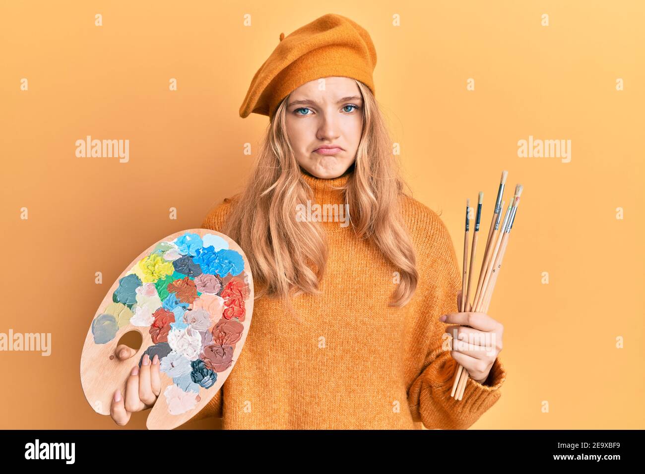 Beautiful young caucasian girl holding paintbrush and painter palette ...