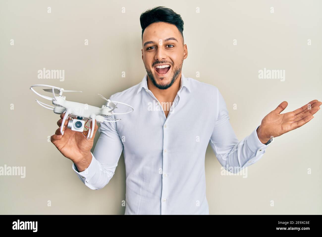 Young arab man using drone celebrating achievement with happy smile and ...