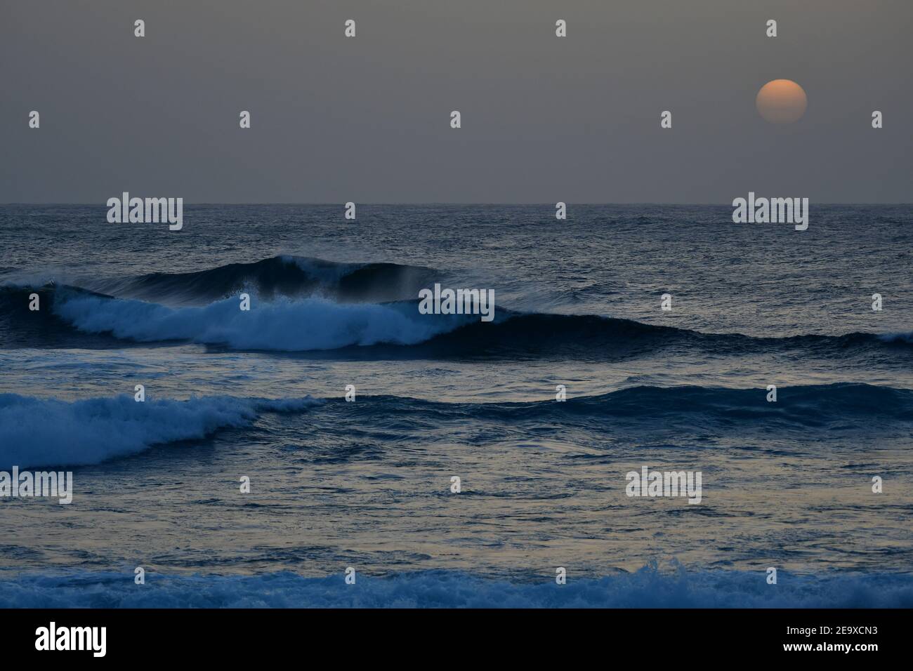 Blue hour: Ocean waves and a full moon Stock Photo - Alamy
