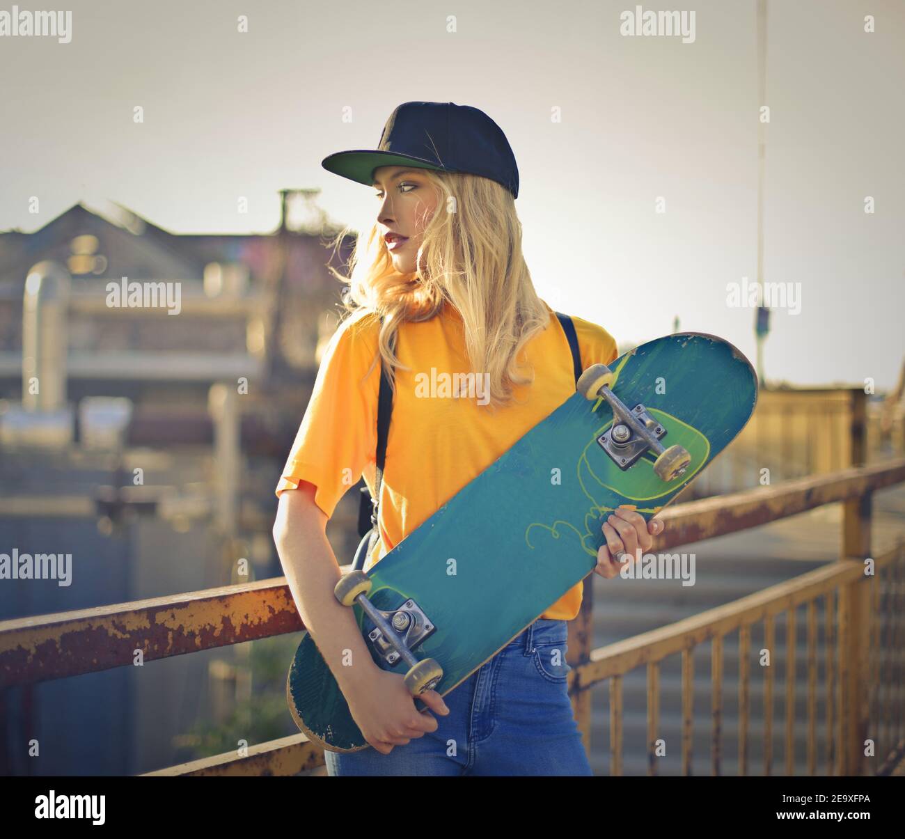 Blonde woman wearing a yellow t-shirt with jeans and a snapback and ...