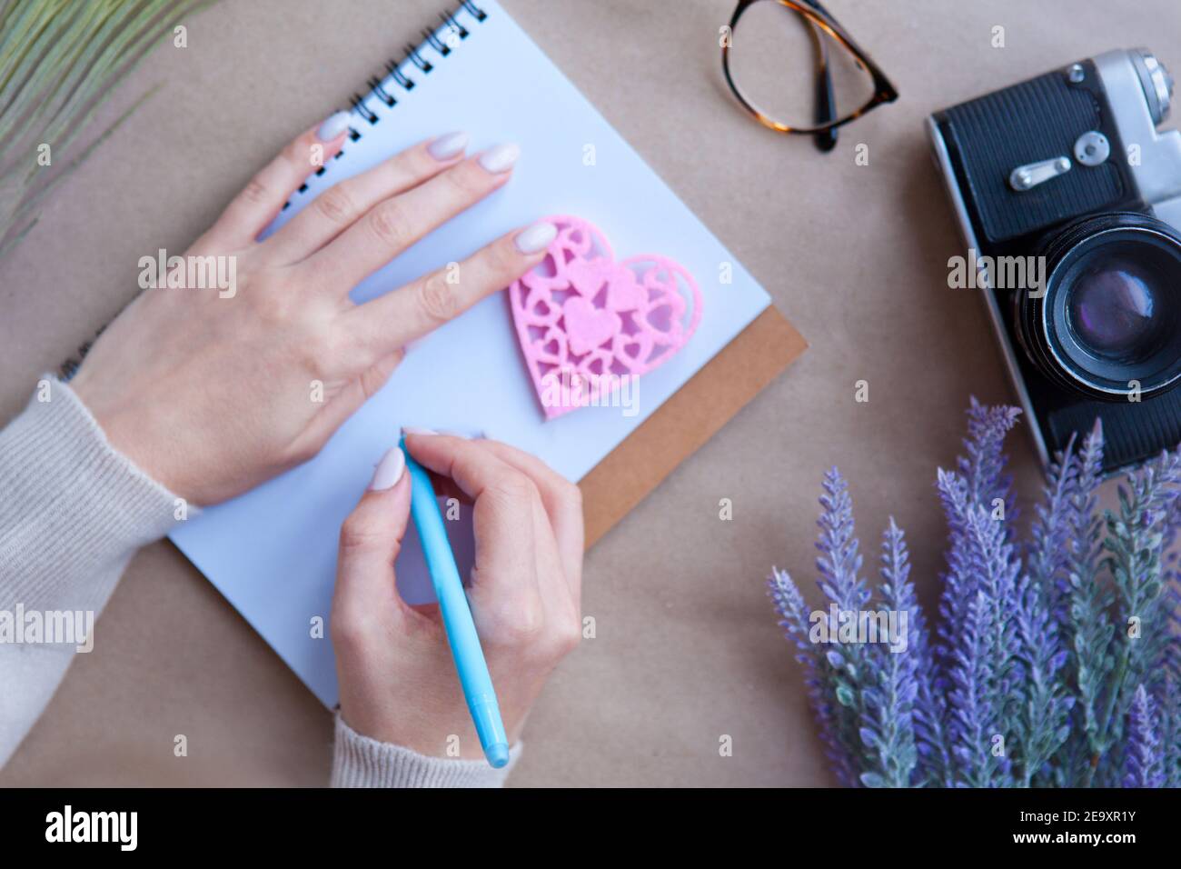 Wooden heart LOVE and woman hands behind notebook on the table and ...