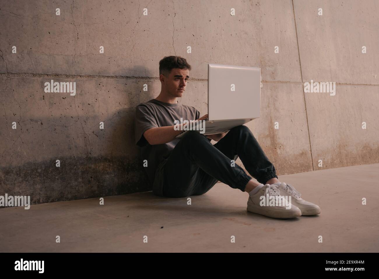 Full length of serious young self employed guy in trendy outfit using ...