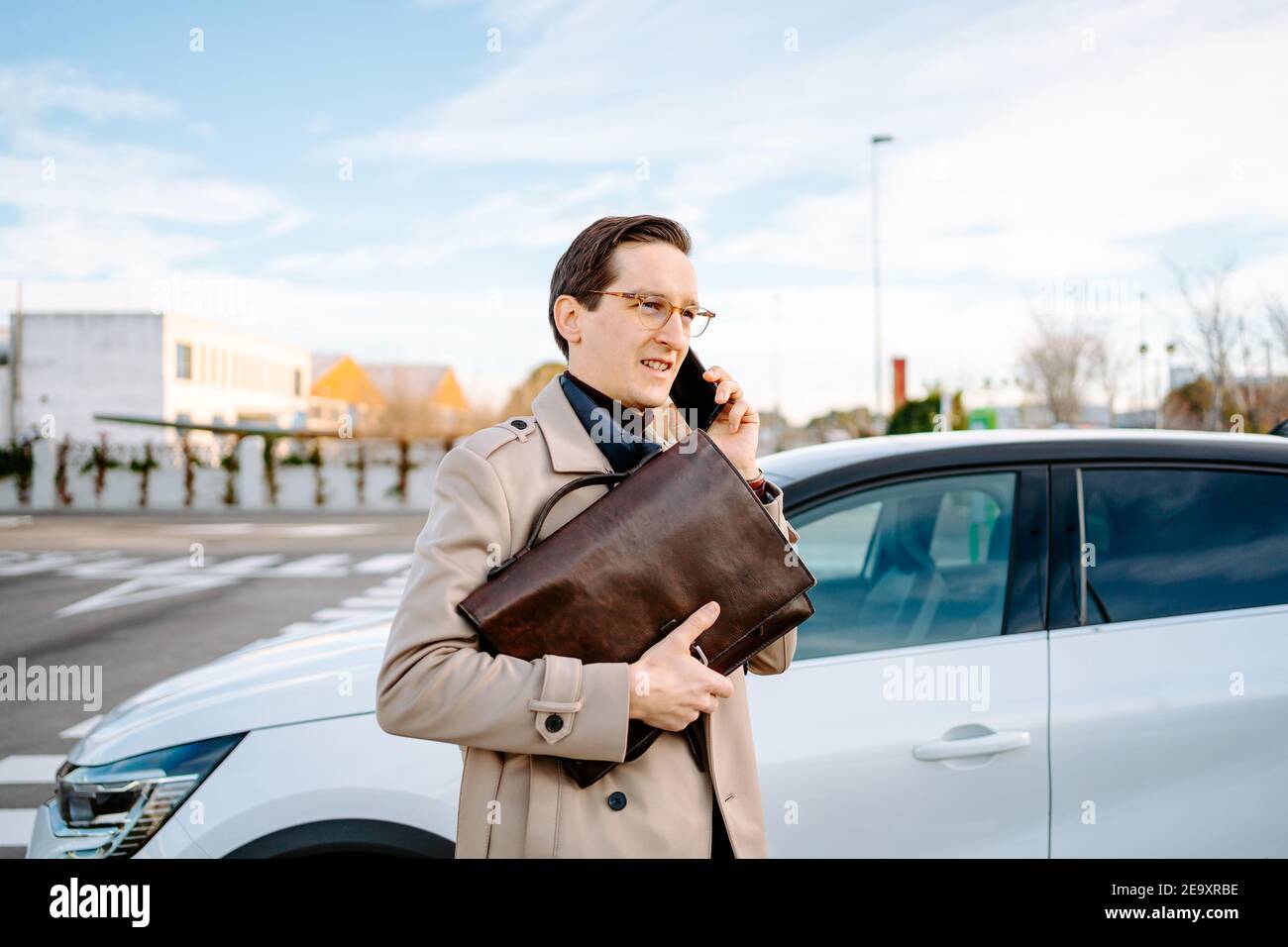 Busy male entrepreneur with attache case standing on parking lot near ...