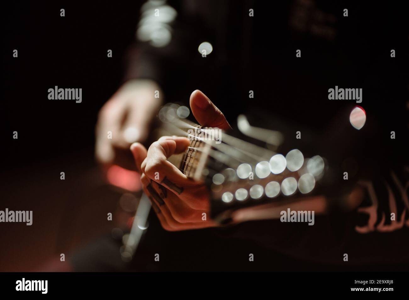 Side view guitarist playing electric guitar while performing in dark ...