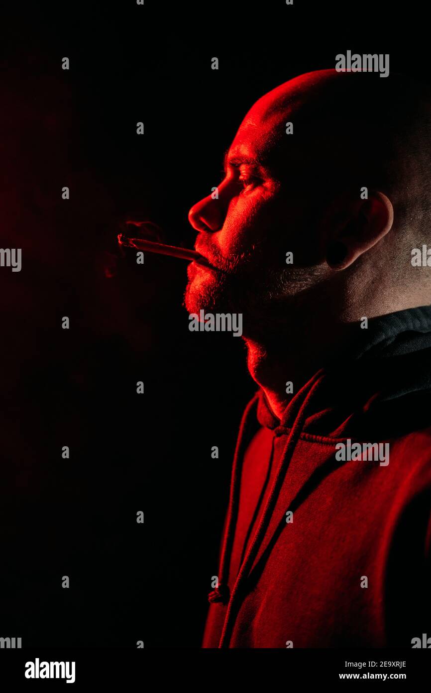 Side view of male rocker with bald head smoking and exhaling fume in ...