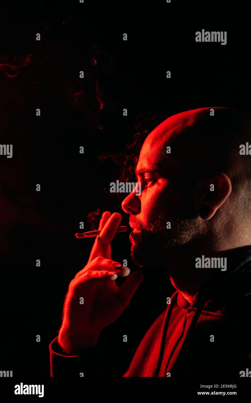 Side view of male rocker with bald head smoking and exhaling fume in ...