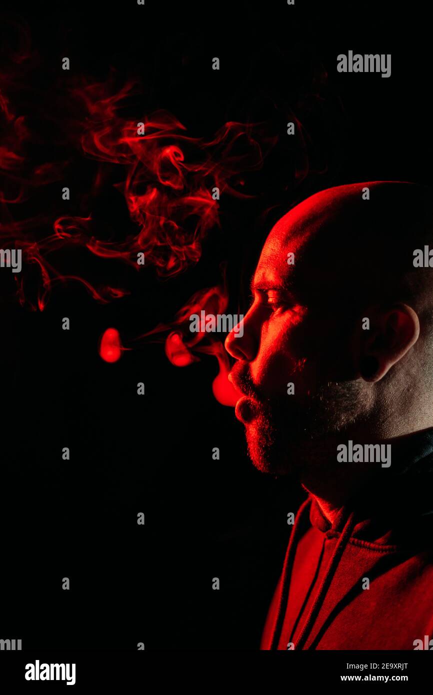 Side view of male rocker with bald head smoking and exhaling fume in ...