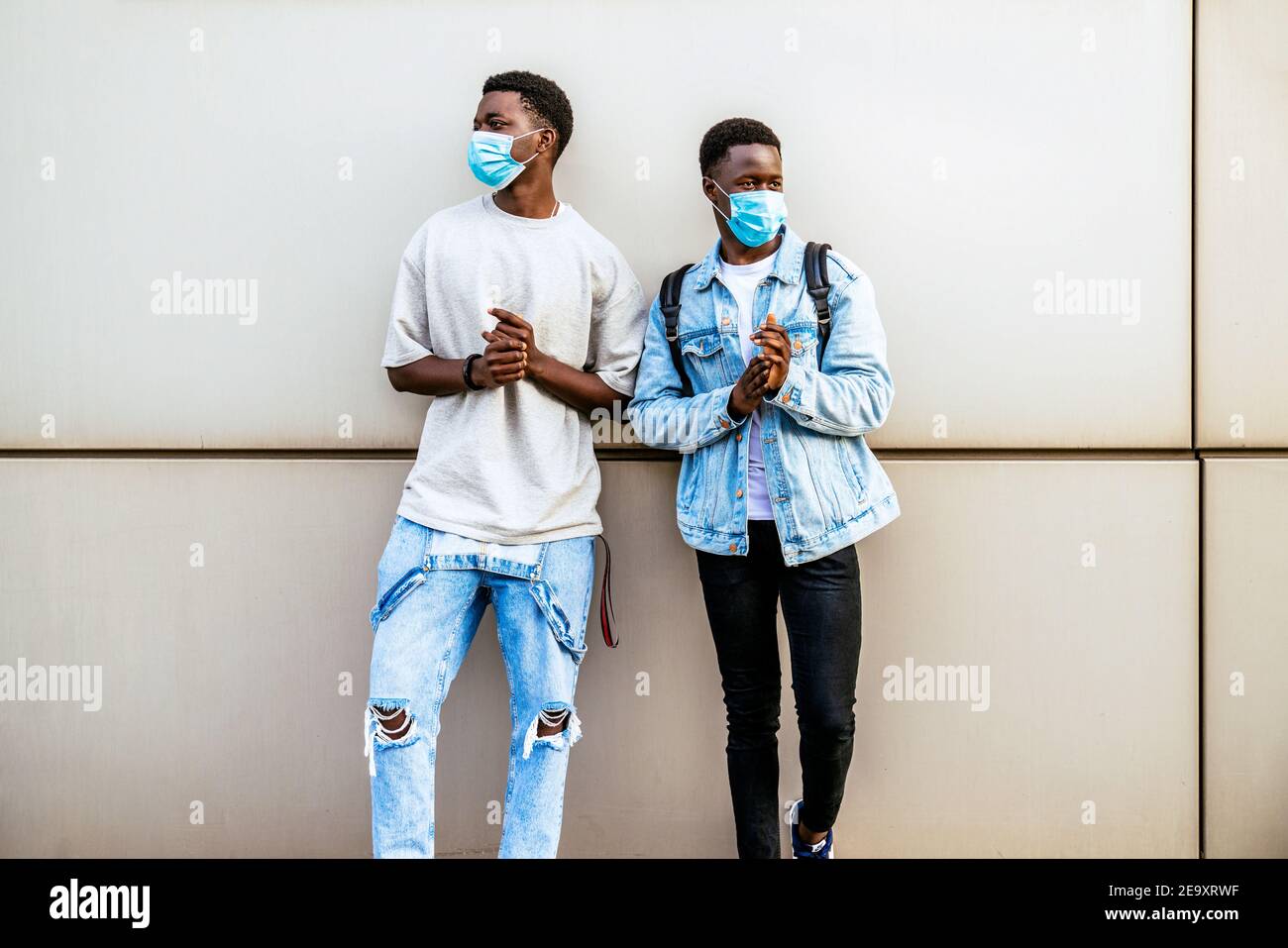 Anonymous young ethnic male partners in face masks and trendy outfit ...