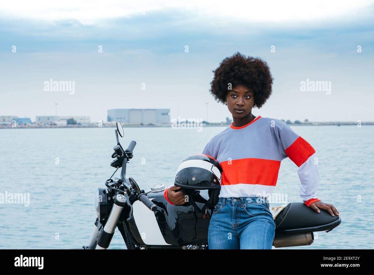Concentrated young black female biker with Afro hair in trendy outfit ...