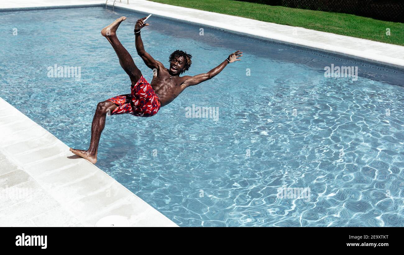 Astonished African American male in shorts and with mobile phone ...