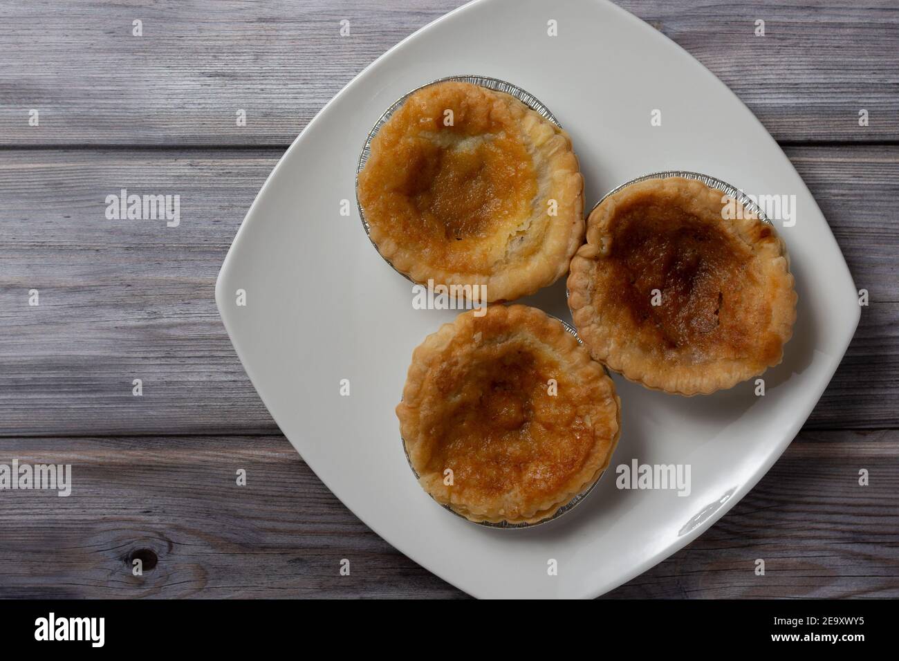 Three traditional bakewell puddings sitting on a white plate viewed top ...