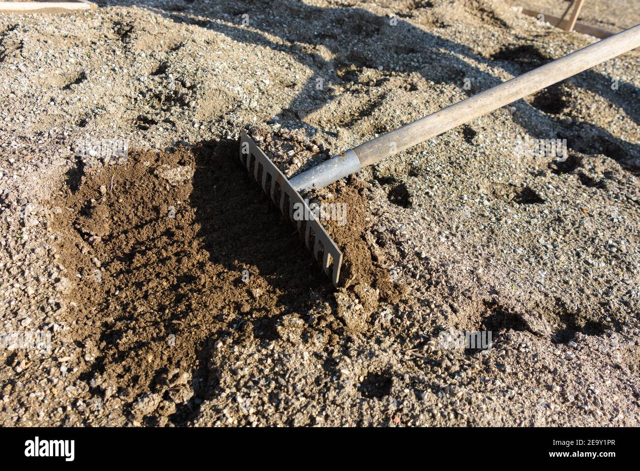 Rakes loosen the garden bed during the spring work on the personal plot ...