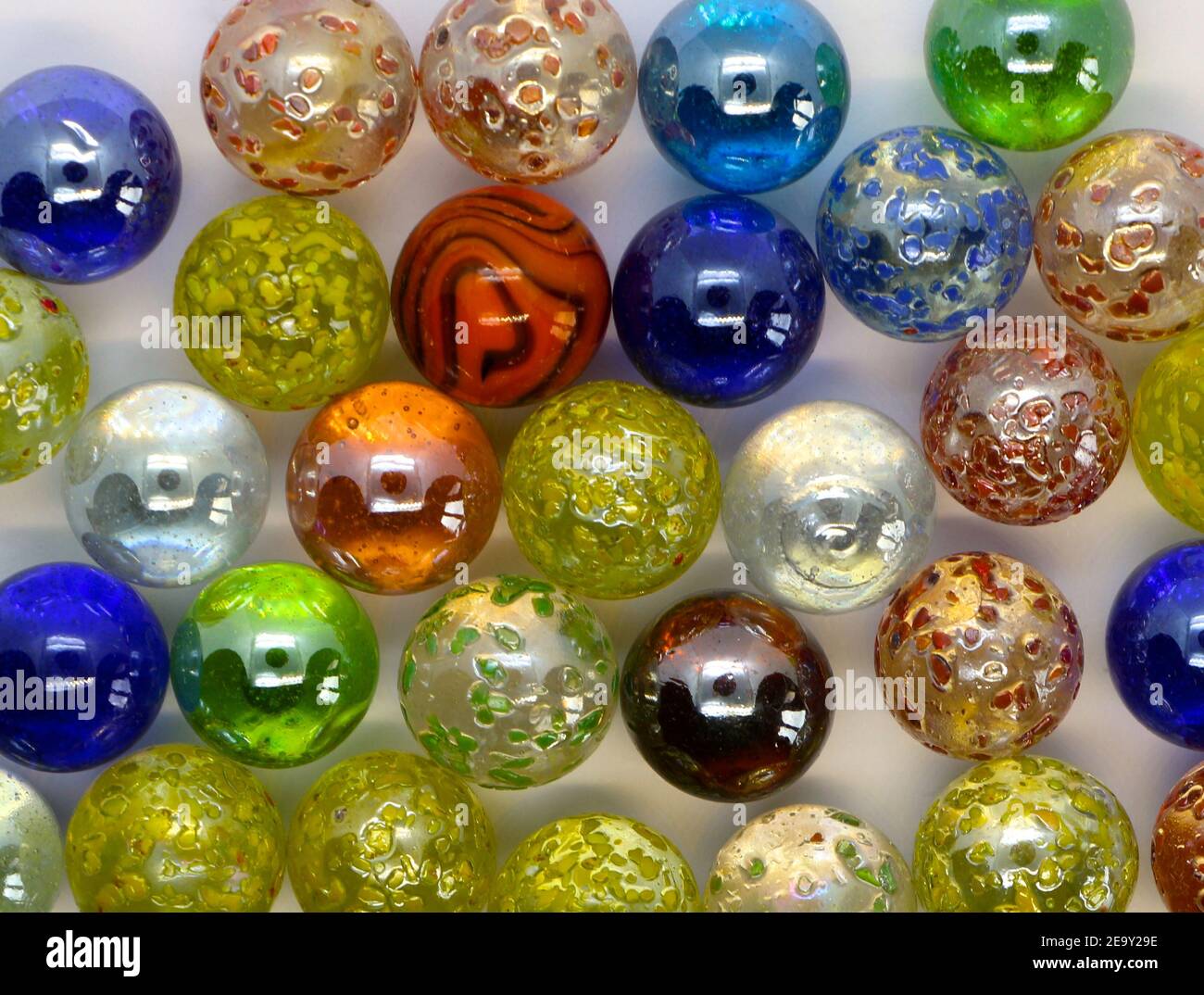 Photo of Glass marbles with patterns and solid colours reflecting light ...