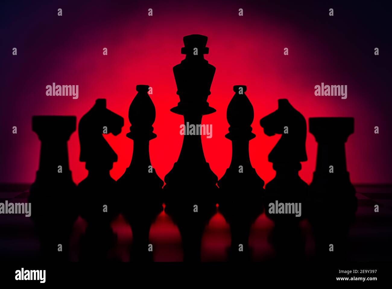Silhouetted chess pieces against a dark red and black gradient ...