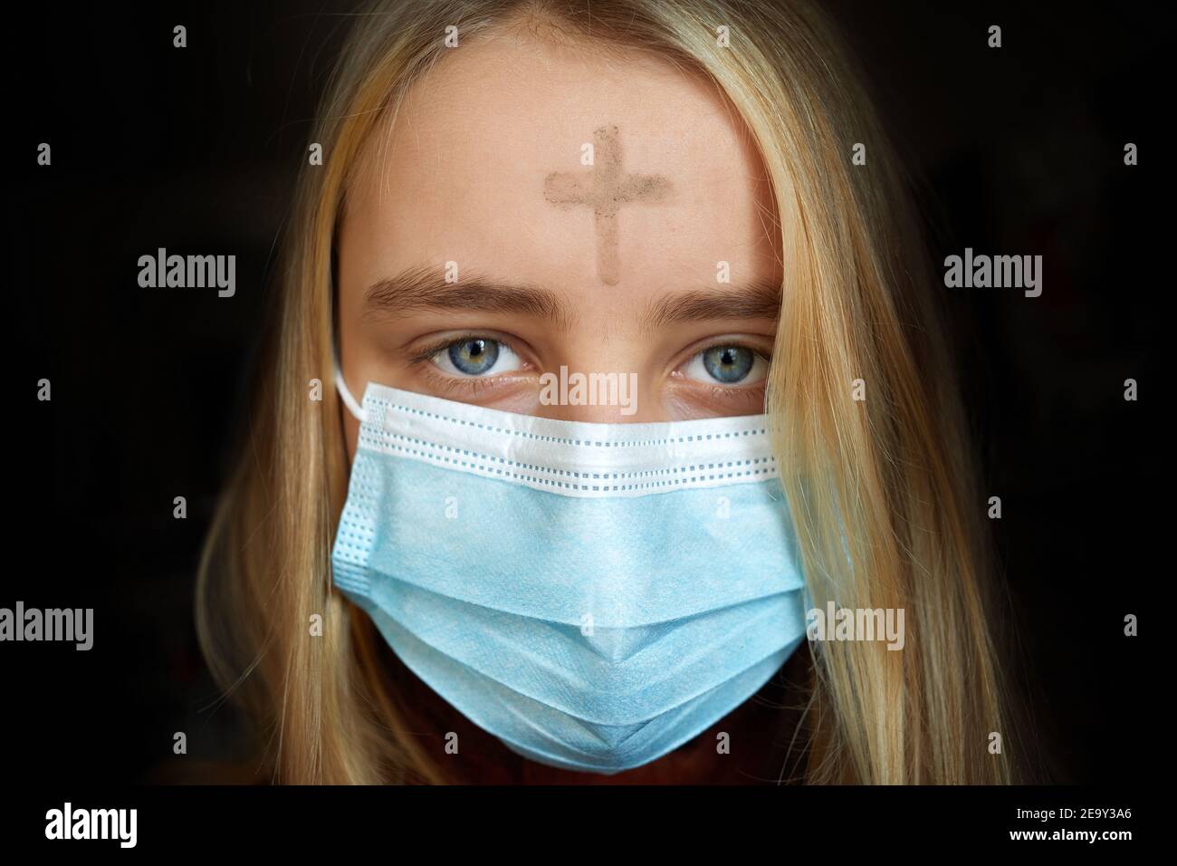 Girl with cross made from ash on forehead with face mask. Ash wednesday ...