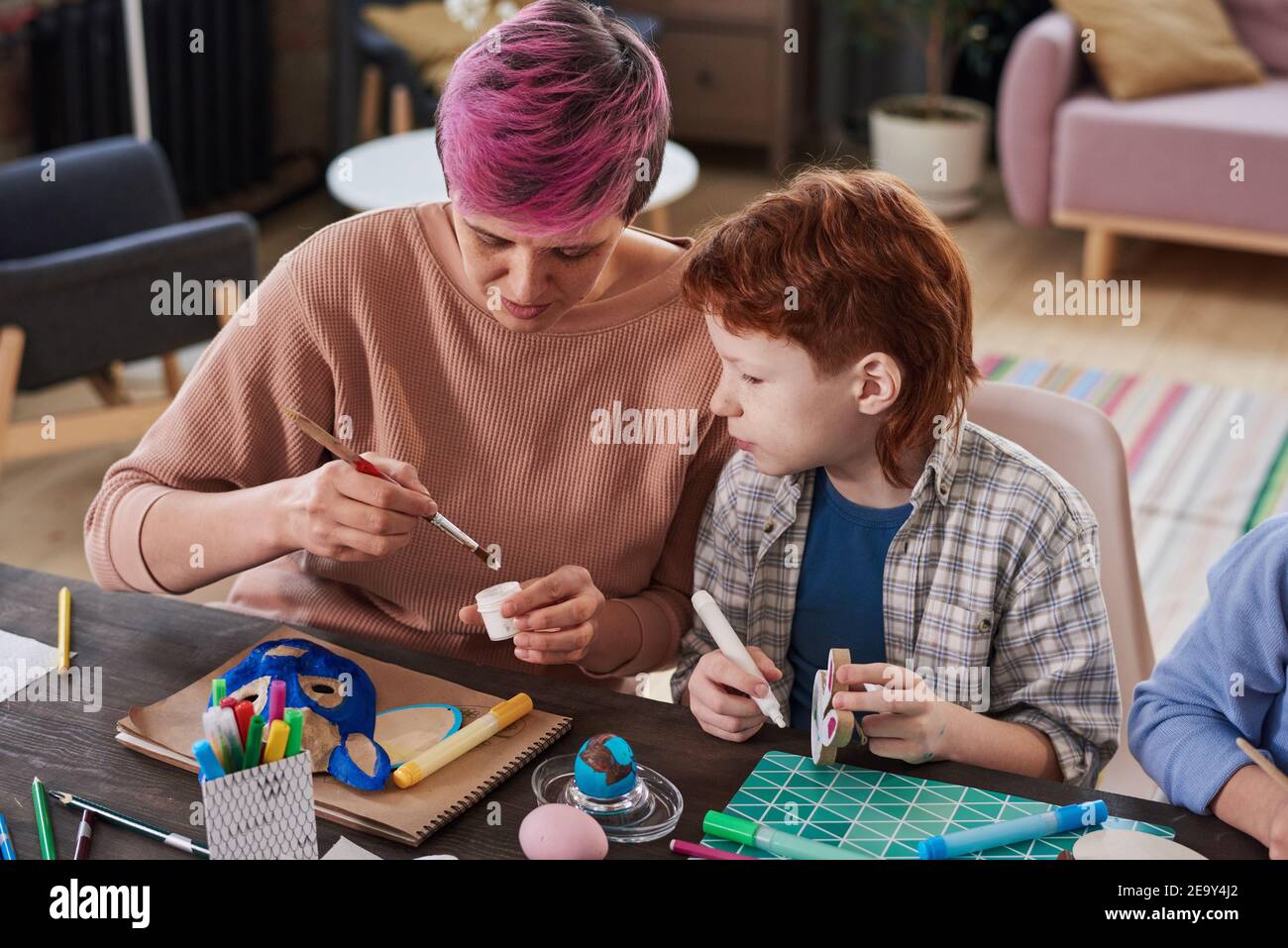 Young woman teaching boy to do craft and painting at the table during art lesson Stock Photo - Alamy