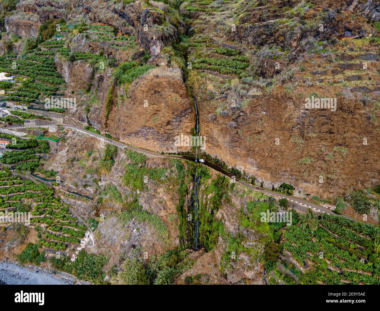 A car drives under Ponta do Sol waterfall on the coast of Madeira ...