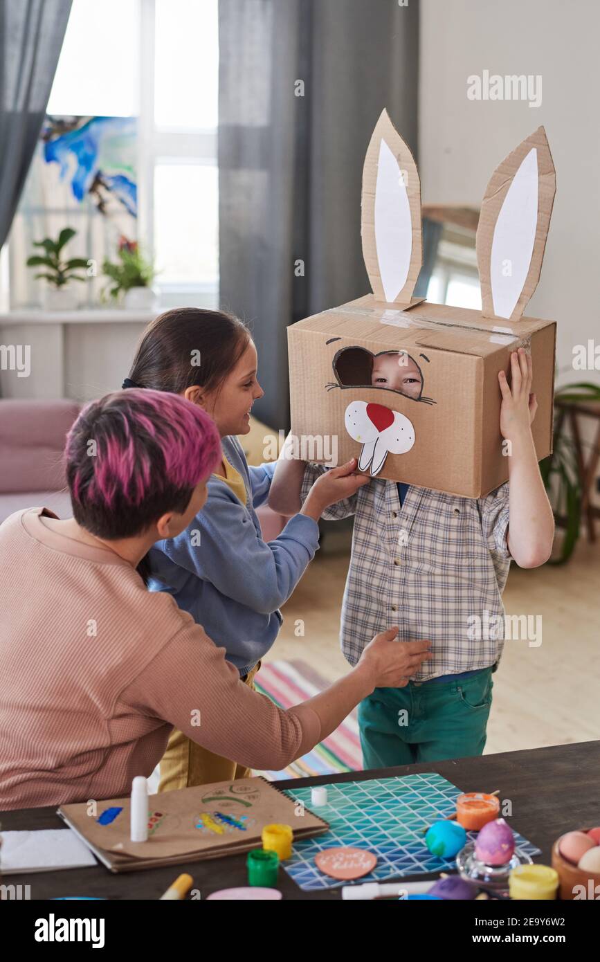 Mother putting rabbit costume from cardboard box on her son preparing ...