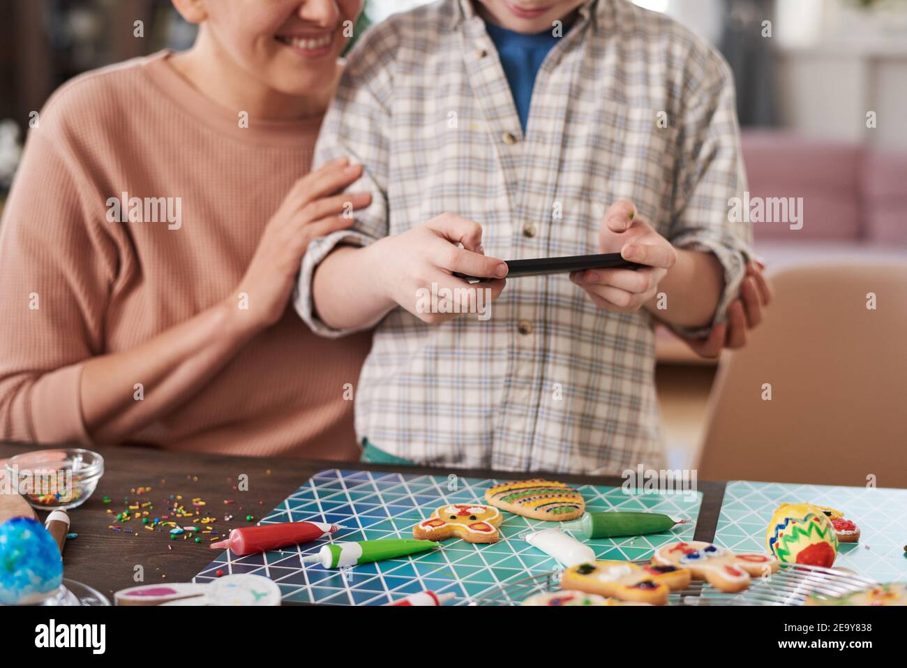 Close-up of boy using mobile phone to make photo of homemade cookies on ...