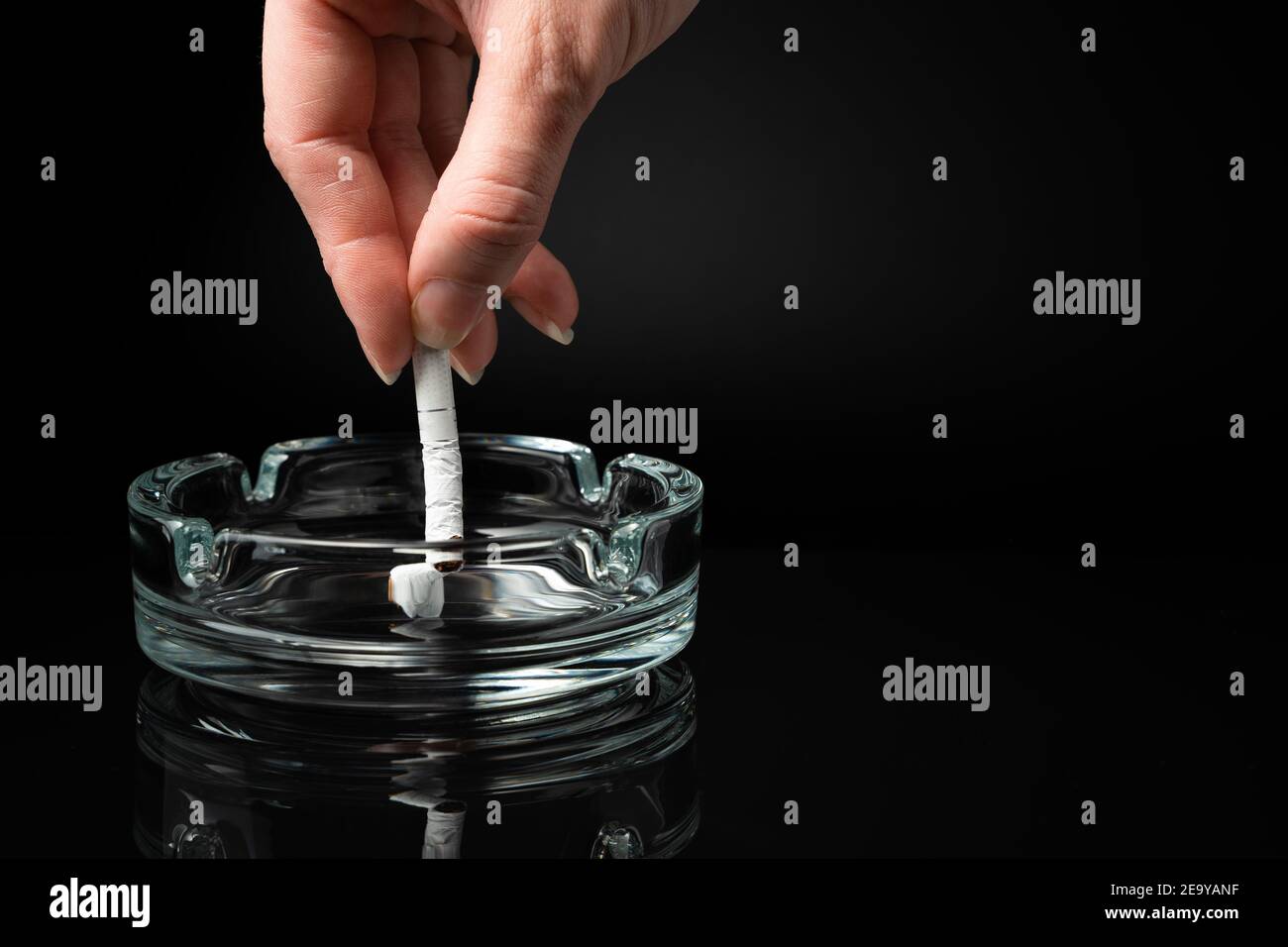 A woman breaks a cigarette on a black background. Side view with the ...