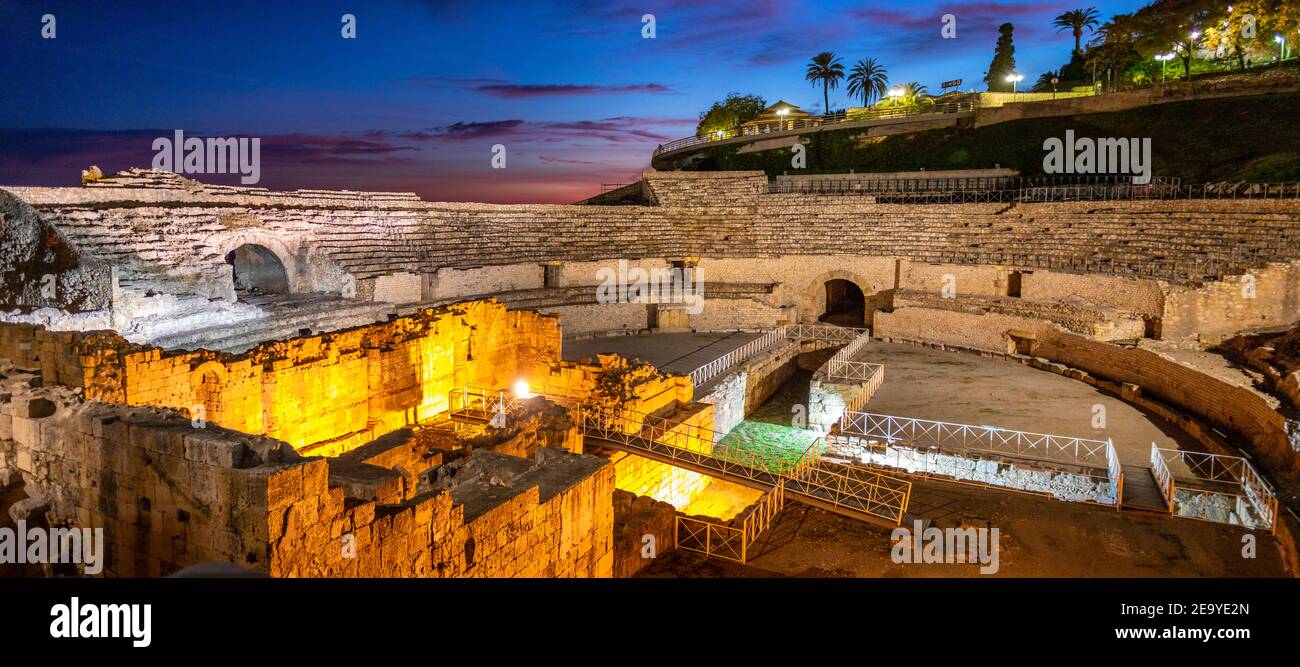 Ruins of ancient Roman amphitheater by night, building illuminated at ...