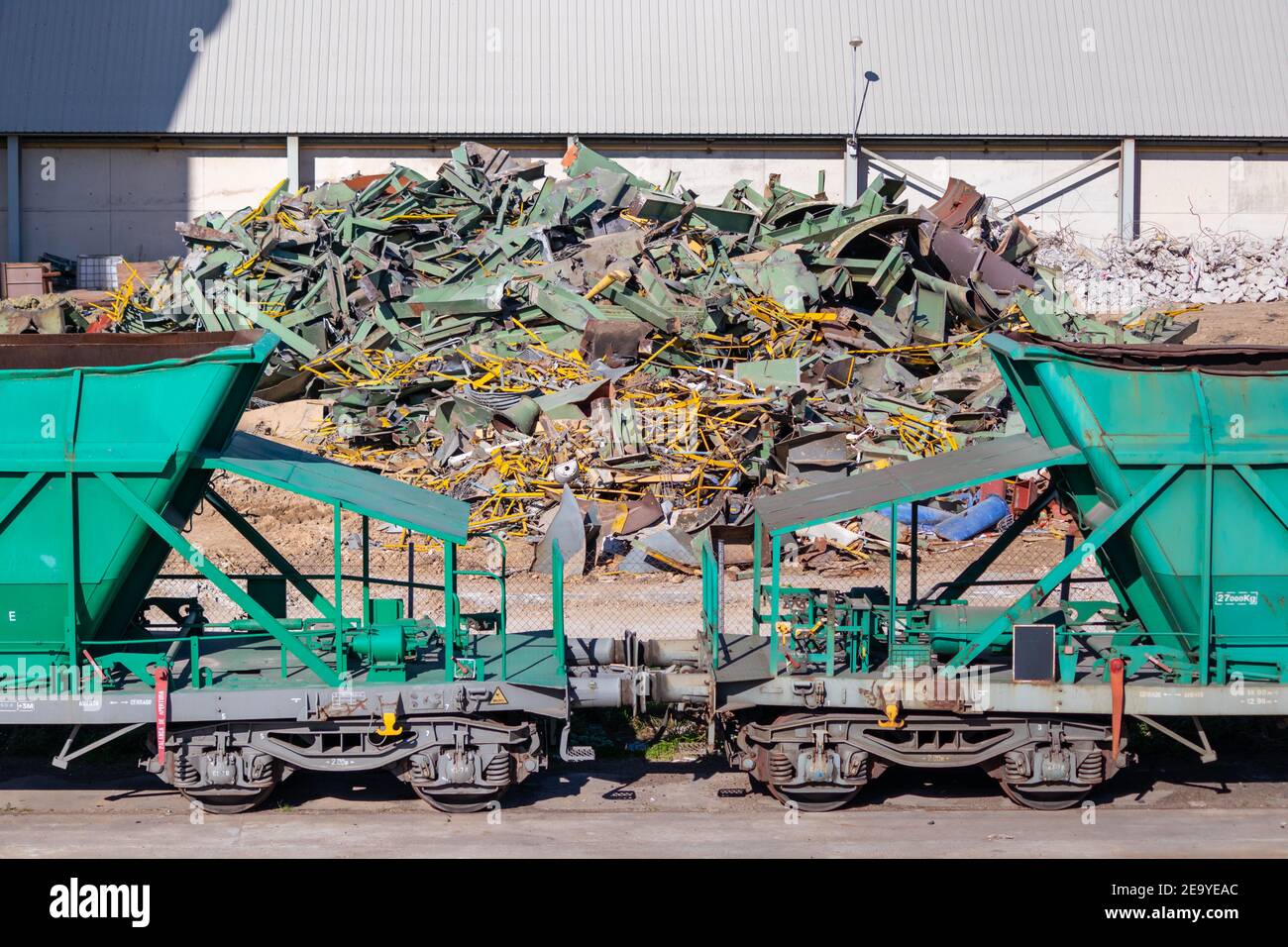 Train loading scrap metal piled outside a factory, train transporting ...