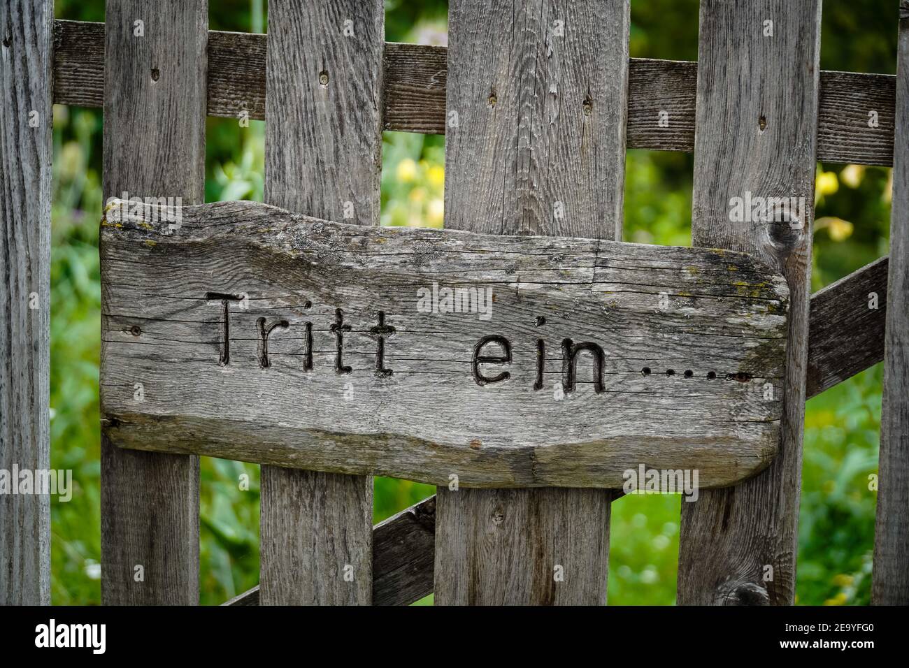 Closeup of a rustic welcome sign in German that translates to "Come in ...