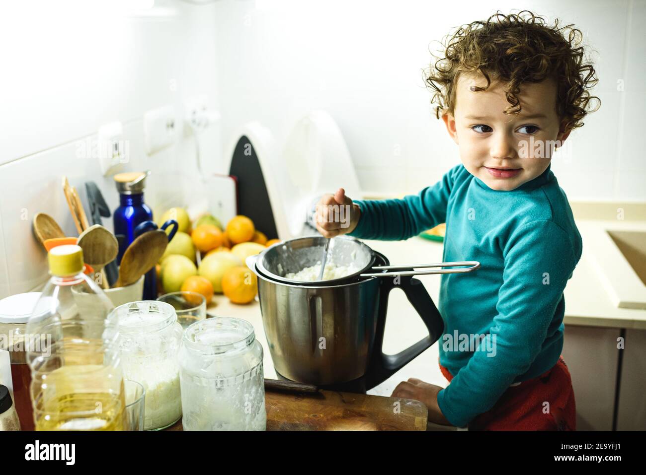 Adorable little girl helps to cook and makes funny and curious ...