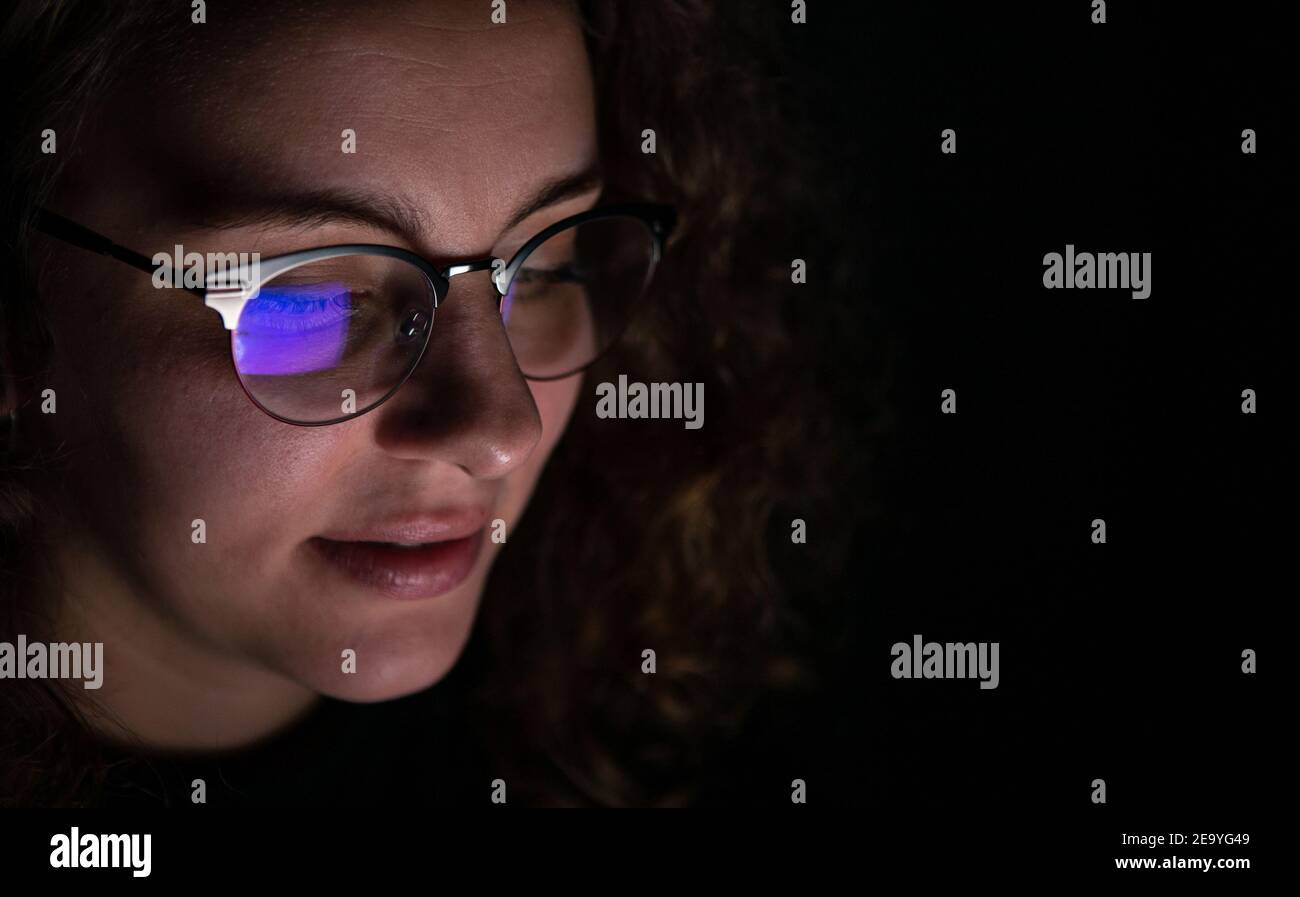 Computer screen reflected in the glasses of a woman who works at night. Overwork concept Stock ...