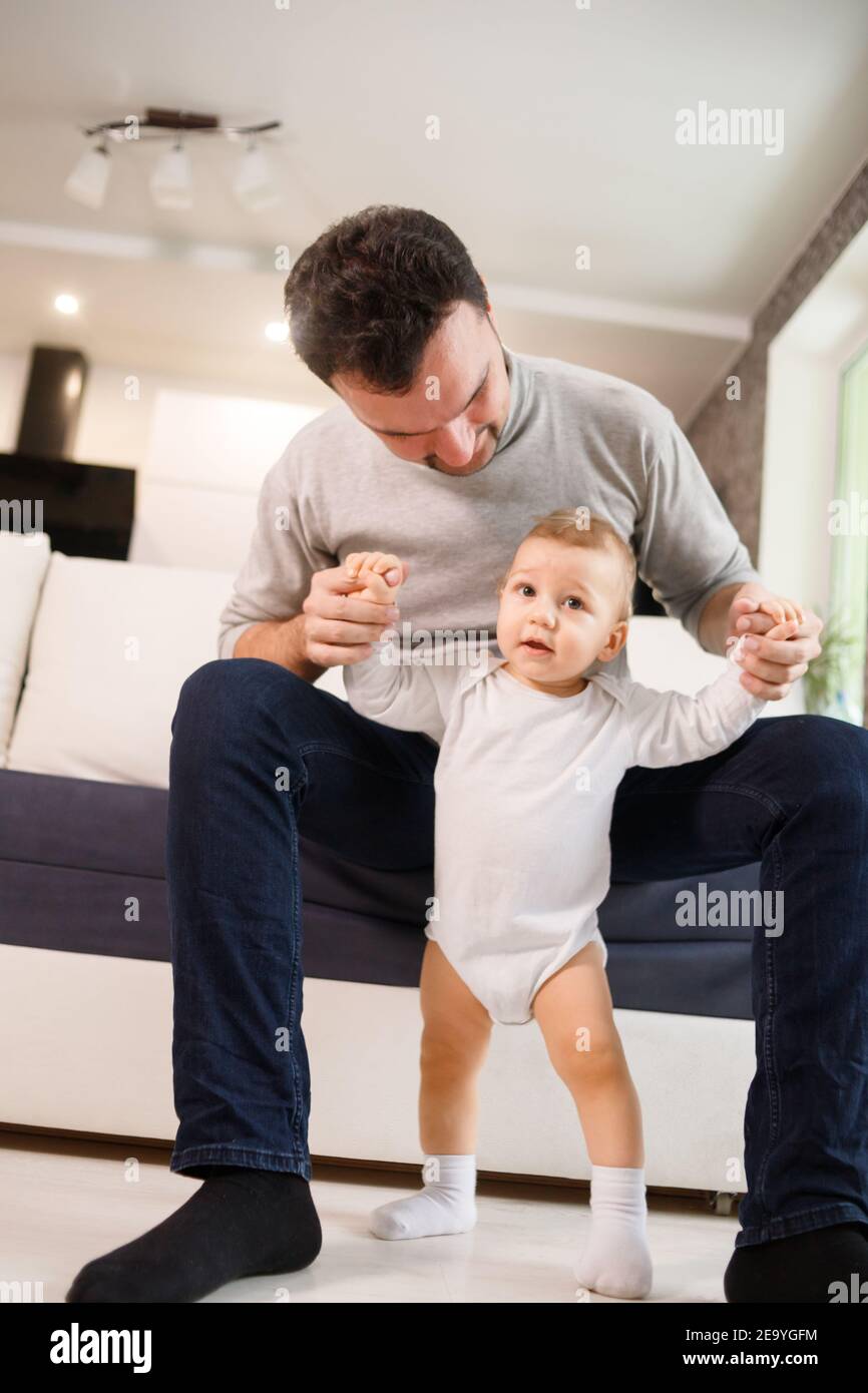 Father teaching a baby to walk in living room at home Stock Photo - Alamy