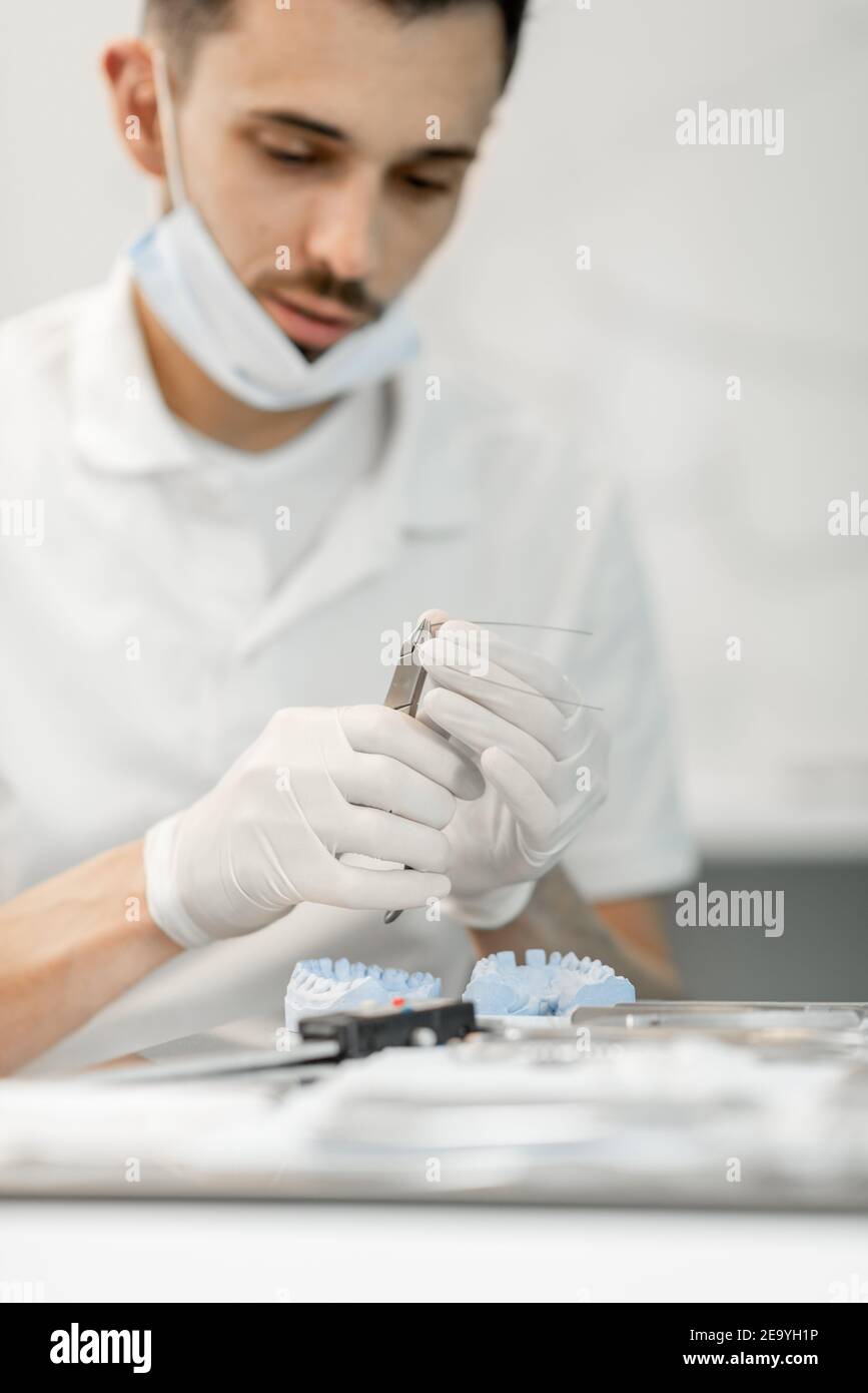 Dental technician working with a model of teeth and dental braces Stock ...