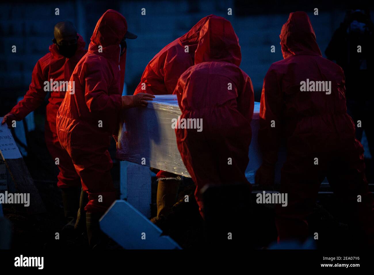 Grave diggers bury a coffin of a Covid-19 coronavirus victim at a ...