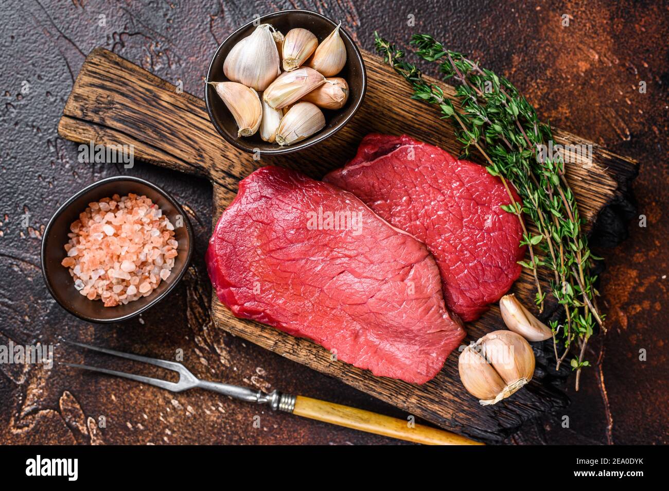 Raw rump beef meat steaks on butcher wooden board. Dark background. Top ...