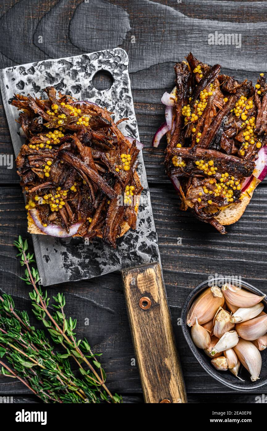 Brisket Sandwich with smoked beef meat on a meat cleaver. Black wooden ...