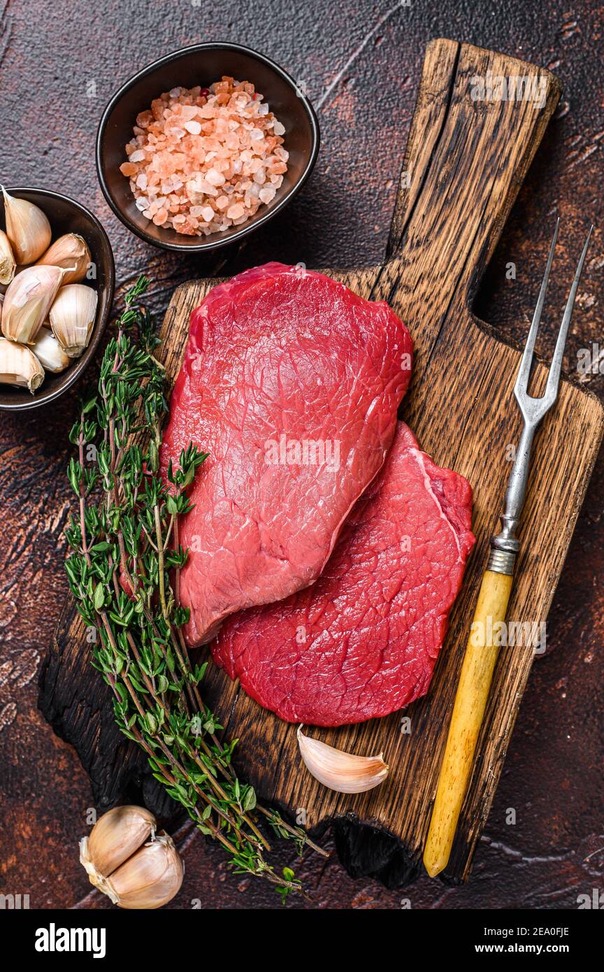 Raw rump beef meat steaks on butcher wooden board. Dark background. Top ...