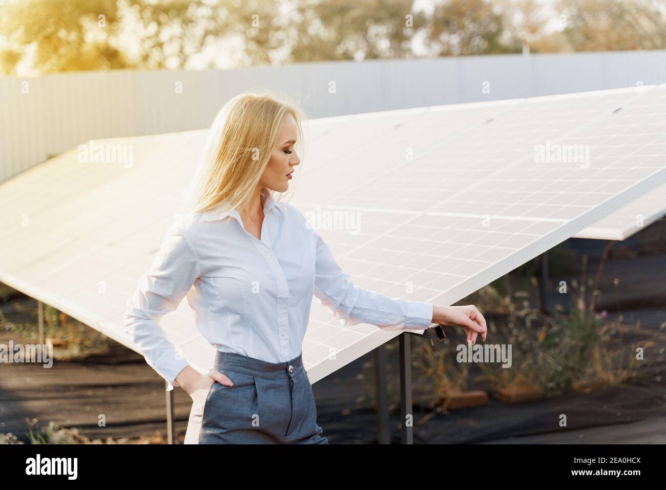 Girl stand and look at solar panels row on the ground with sun light ...
