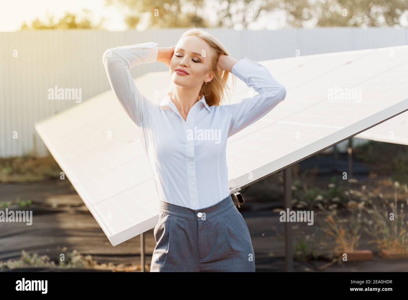 Girl stand and look right side near solar panels row on the ground with sun light. Woman ...