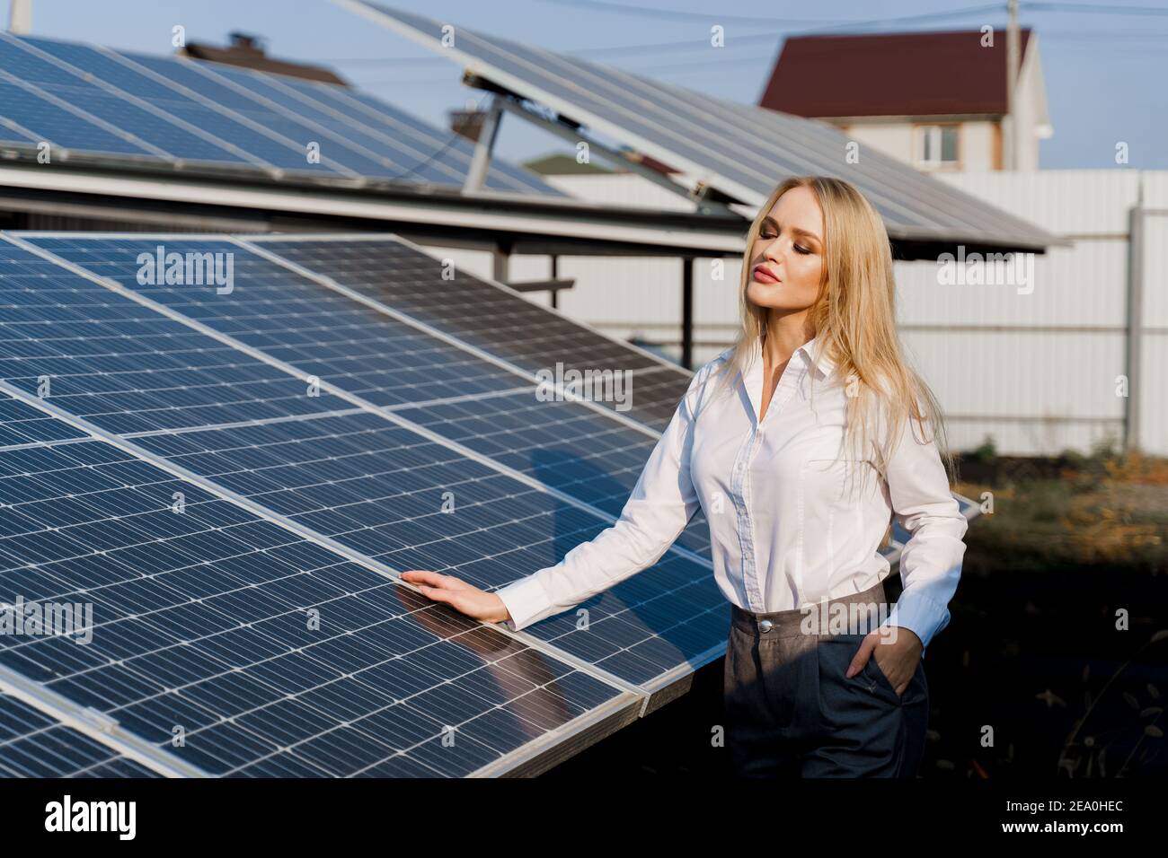 Woman leans on solar panels. Blonde dressed white formal shirt on the ...