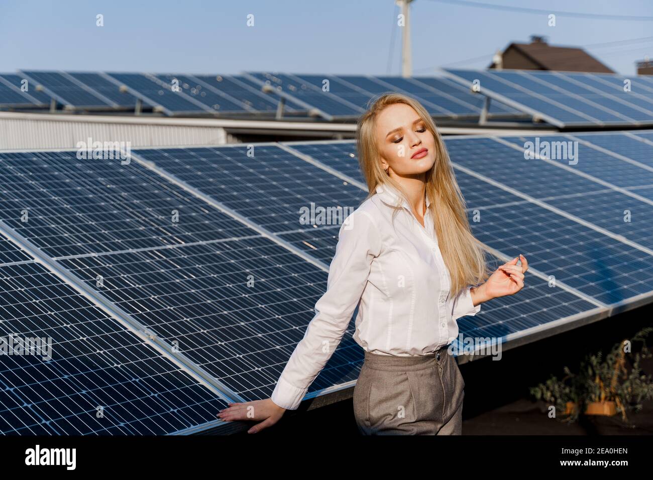 Woman leans on solar panels. Blonde dressed white formal shirt on the ...