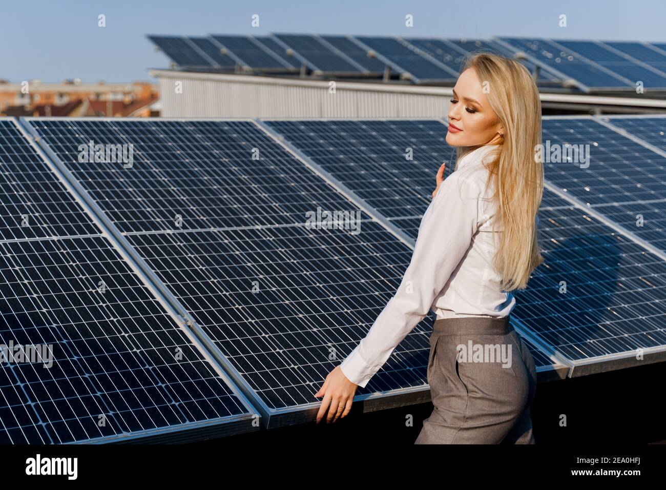 Woman leans on solar panels. Blonde dressed white formal shirt on the ...