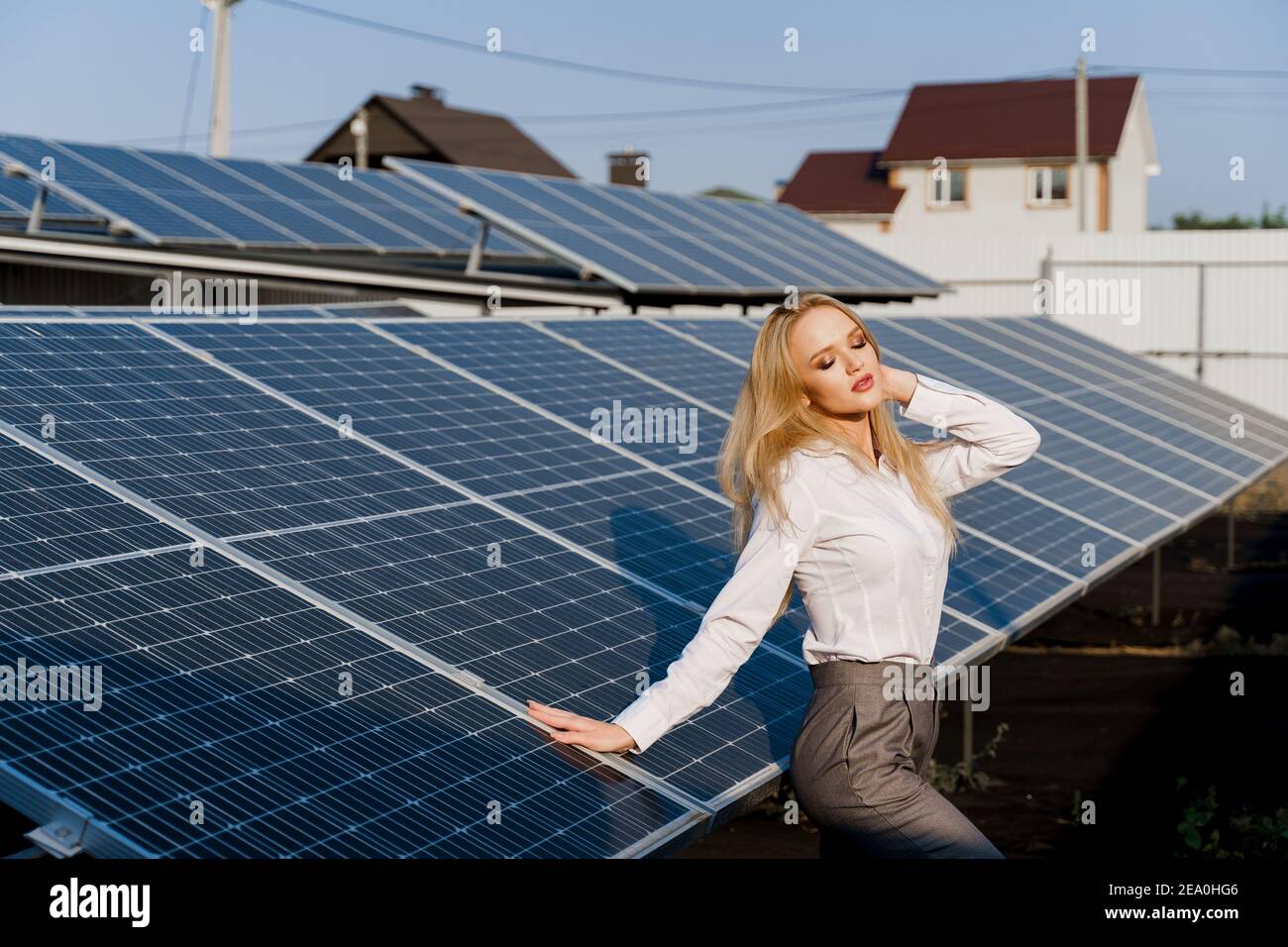 Woman leans on solar panels. Blonde dressed white formal shirt on the ...