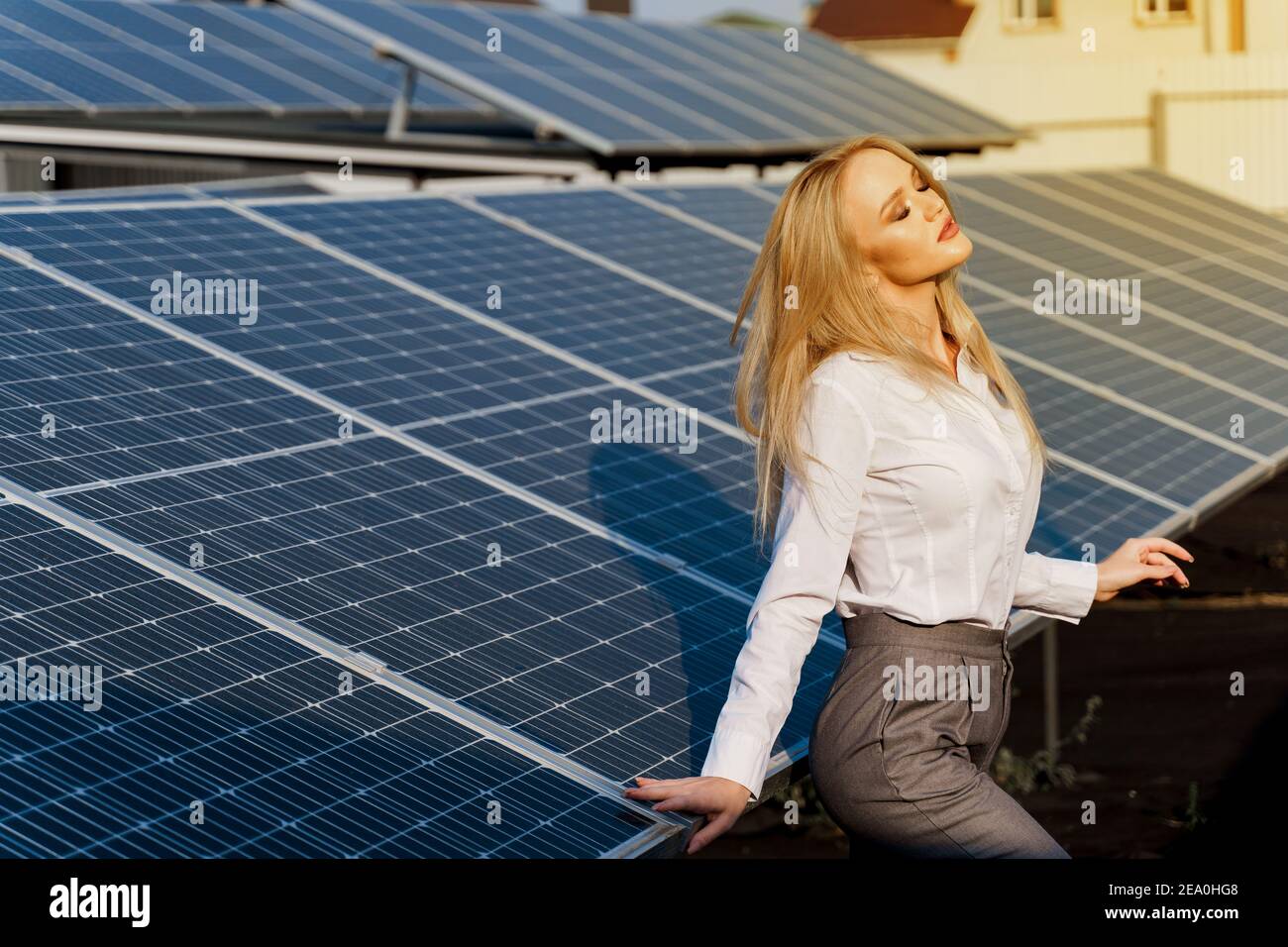 Woman leans on solar panels. Blonde dressed white formal shirt on the ...