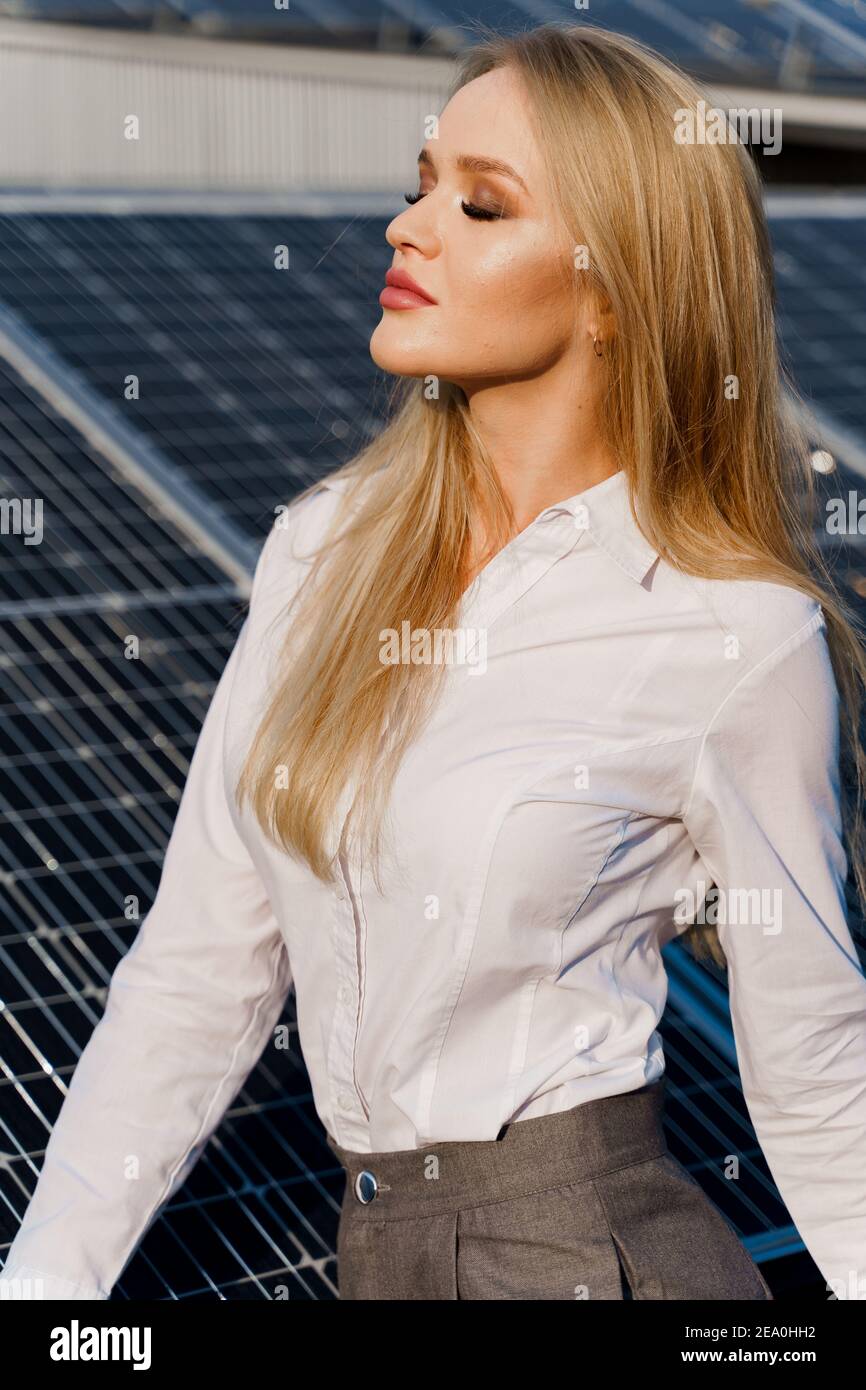 Close-up portrait of blonde model near solar panels. Woman dressed ...