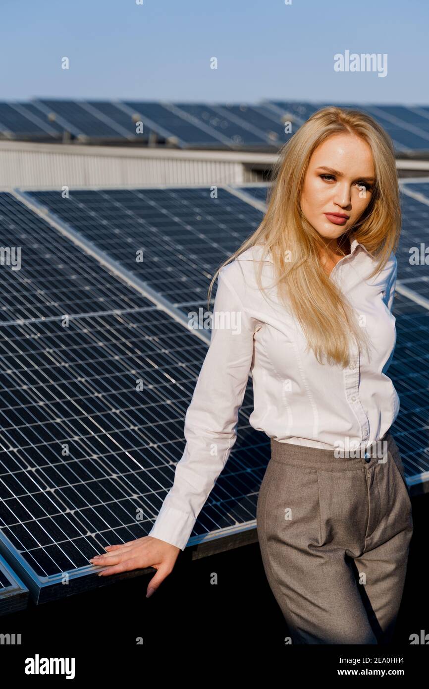 Woman leans on solar panels. Blonde dressed white formal shirt on the ...
