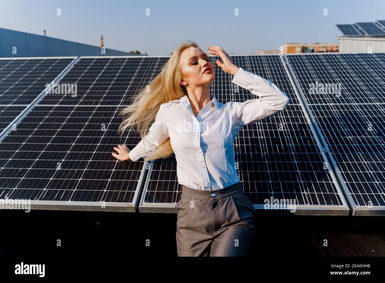 Woman leans on solar panels. Blonde dressed white formal shirt on the ...
