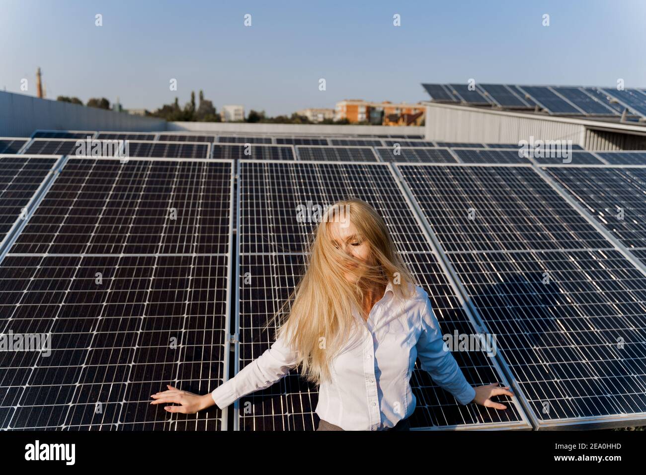 Woman leans on solar panels. Blonde dressed white formal shirt on the ...