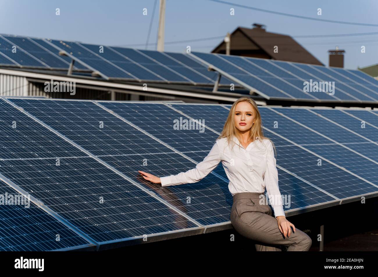 Girl and solar panels stands in row on the ground at sunset. Woman ...
