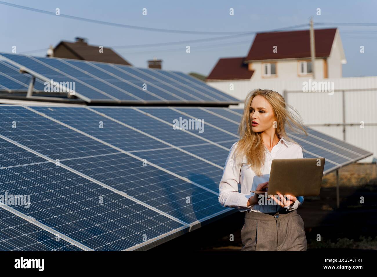 Investor and solar panels. Blonde woman with laptop near blue solar ...