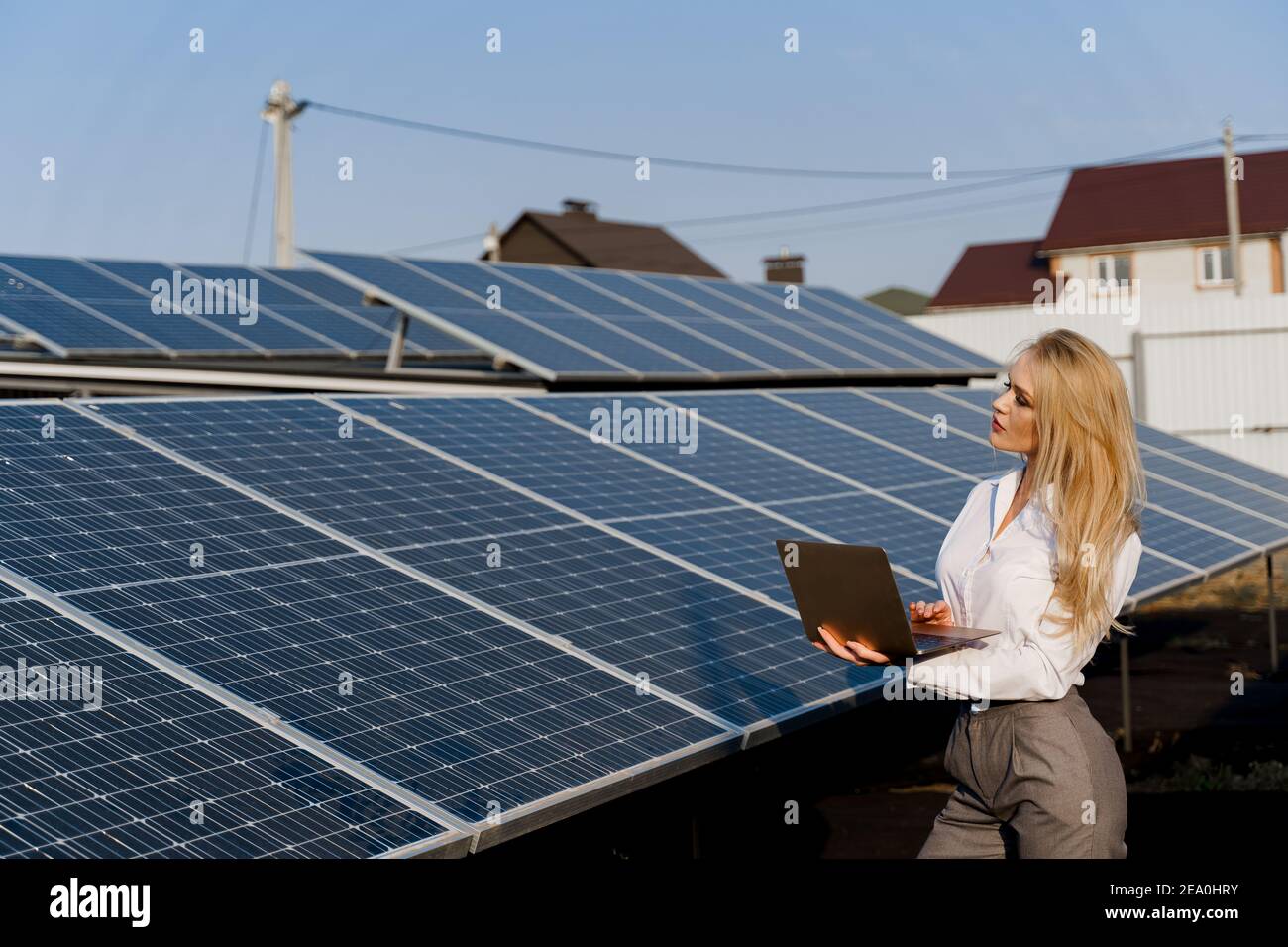 Investor and solar panels. Blonde woman with laptop near blue solar ...