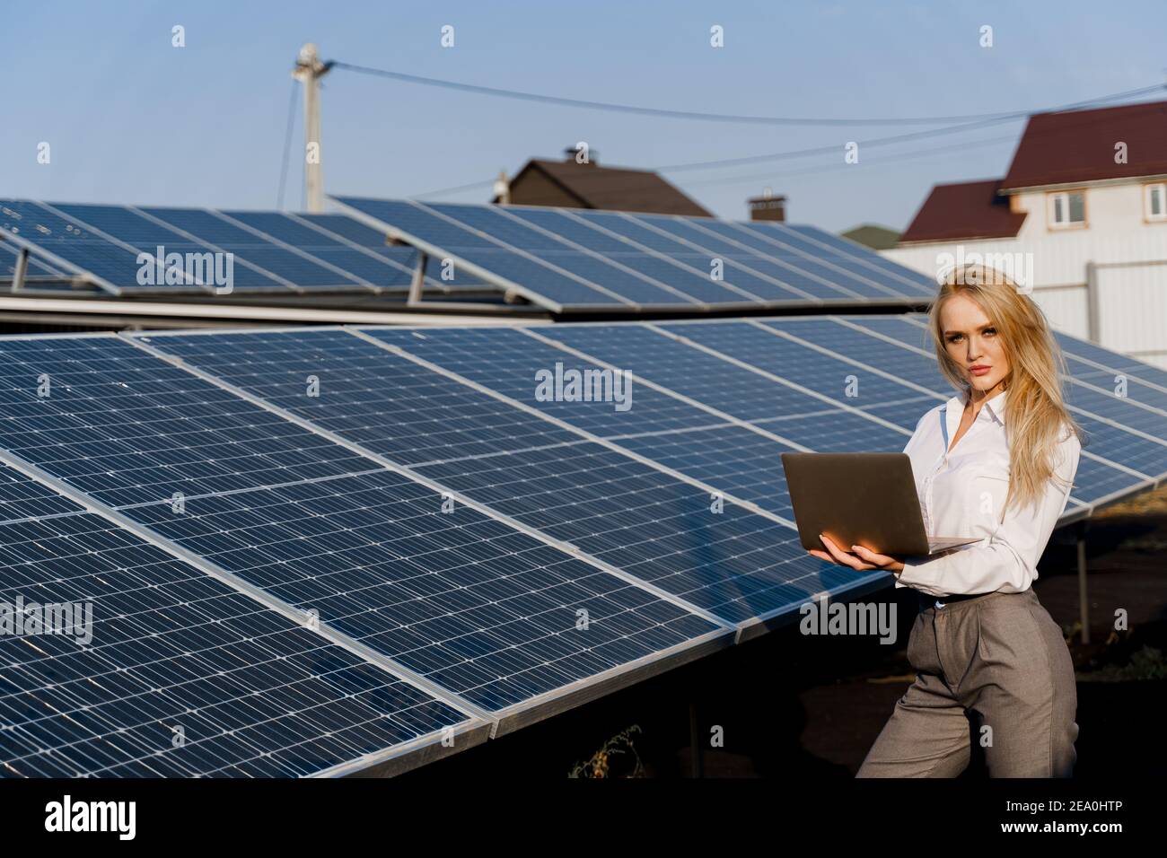 Investor and solar panels. Blonde woman with laptop near blue solar ...